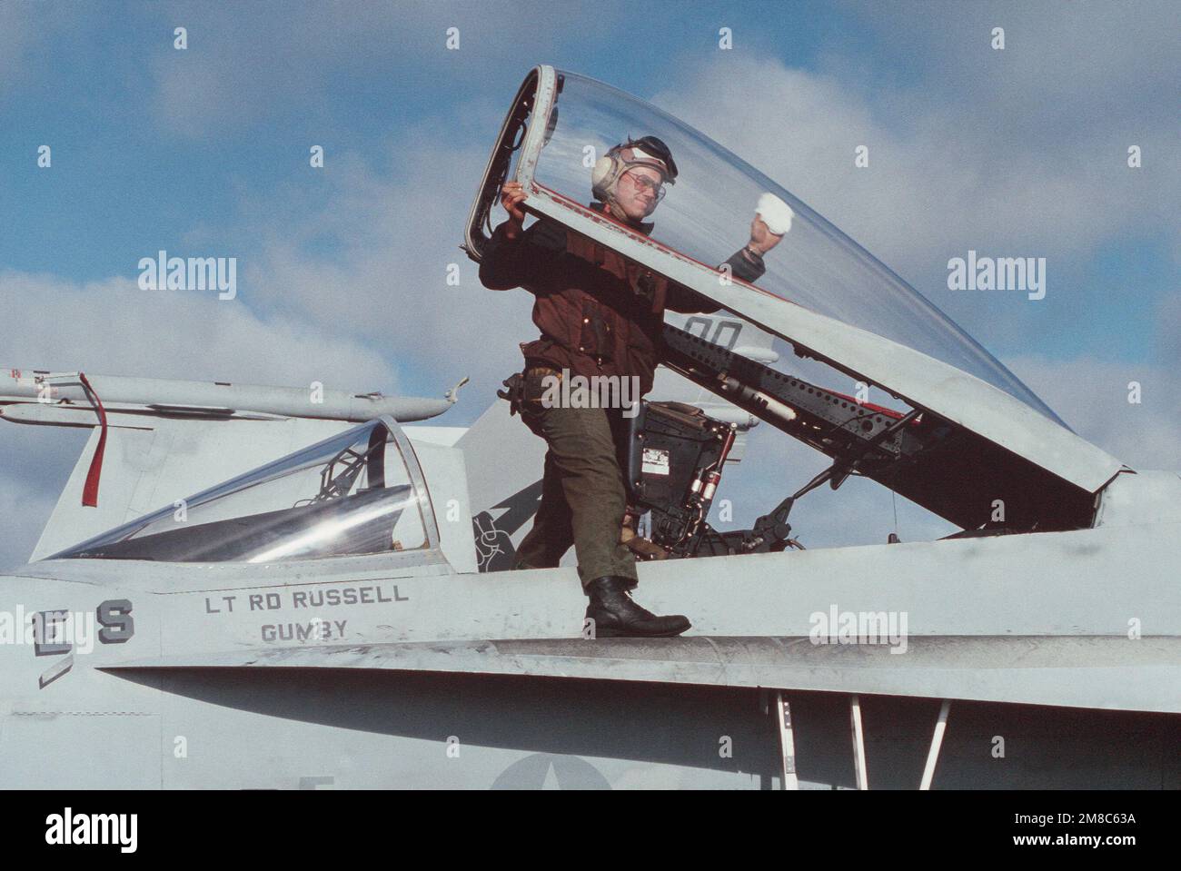A member of the flight deck crew cleans the canopy of an F/A-18 Hornet ...