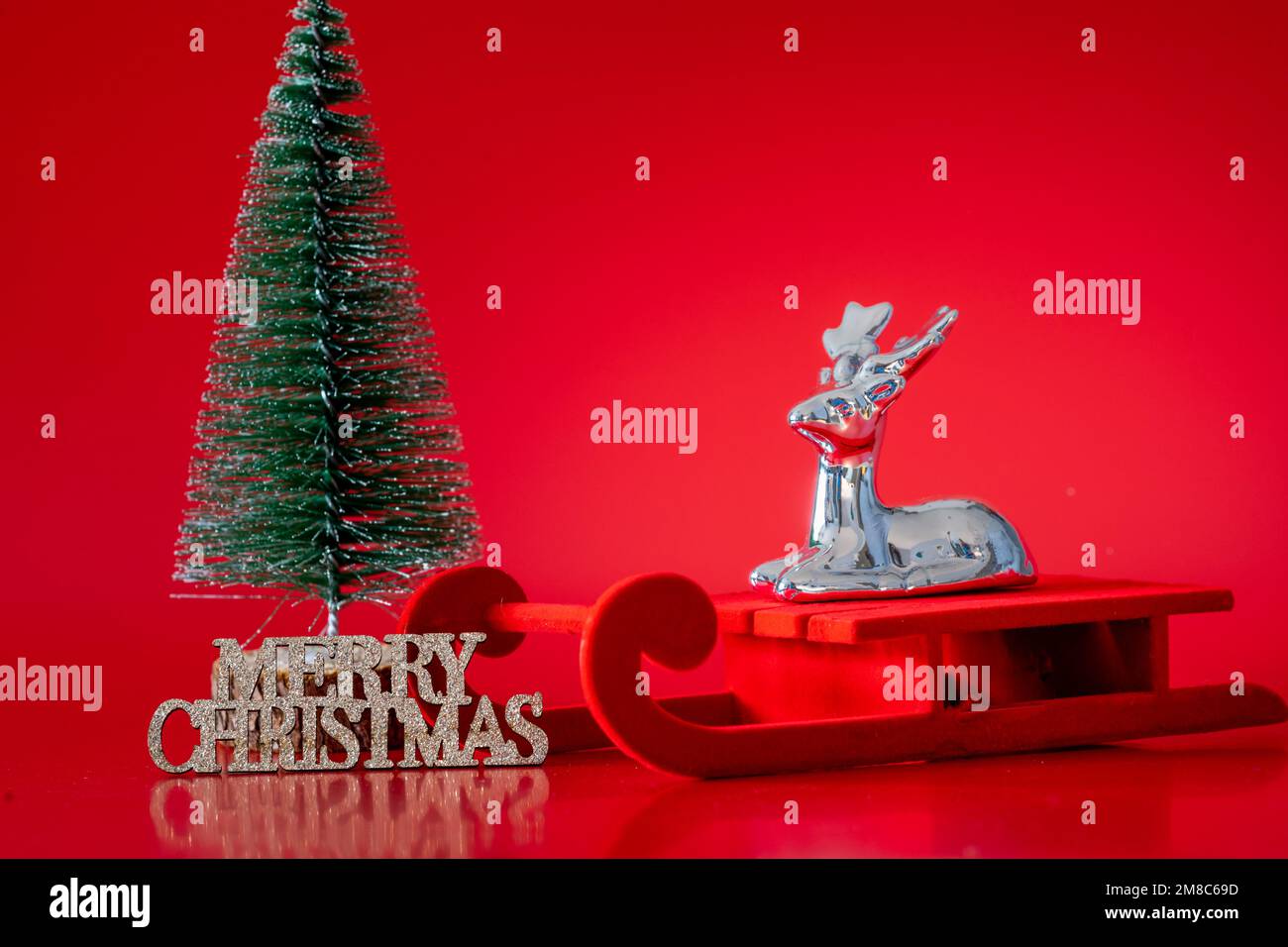 A closeup of a miniature decorative reindeer on a slay next to a ...