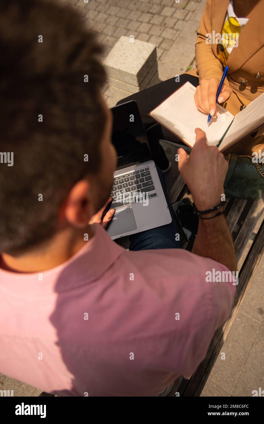 A young businessman is helping out his female colleague with the notes ...