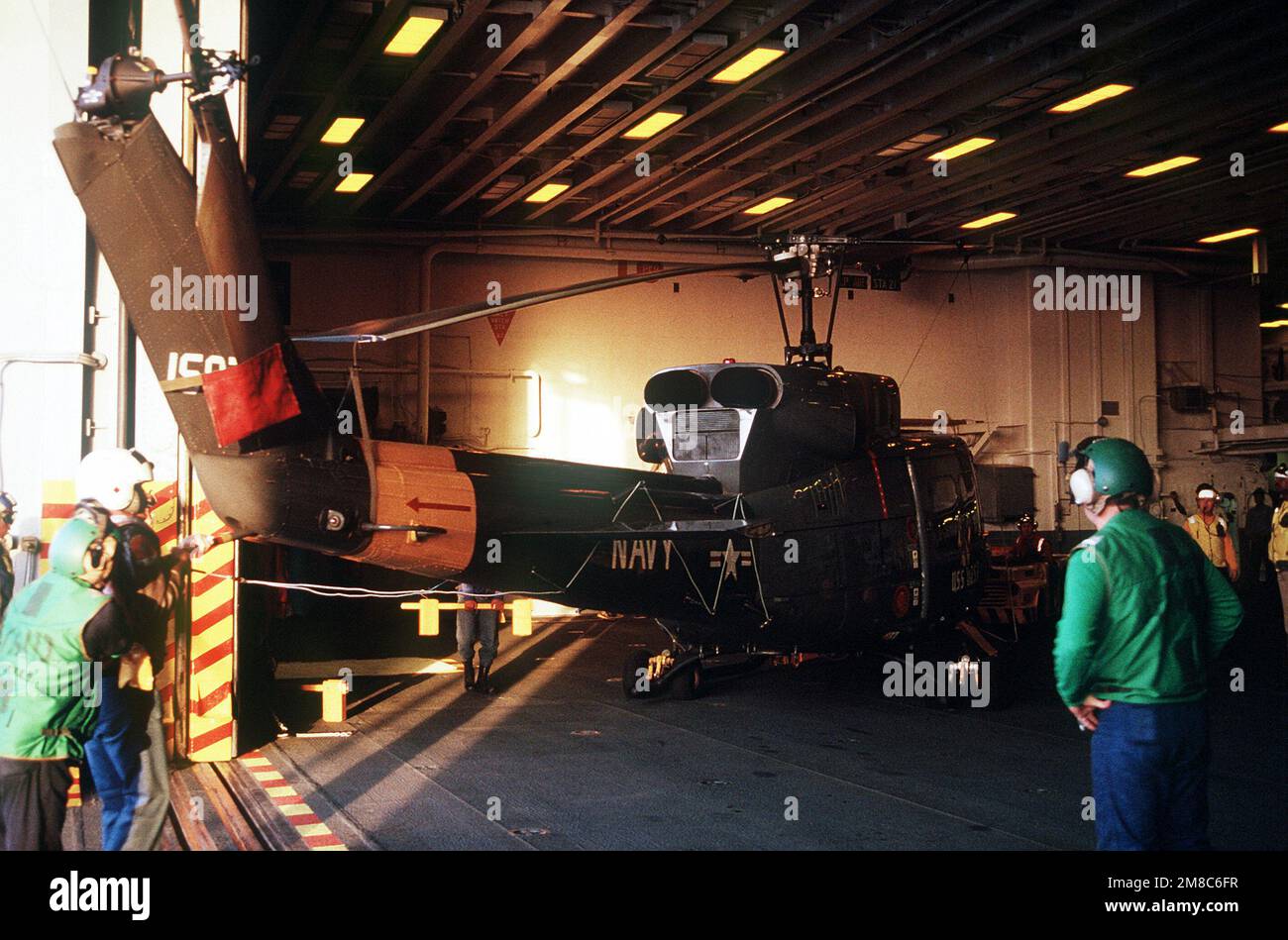 Squadron personnel examine a UH-1N Iroquois helicopter on the hangar ...