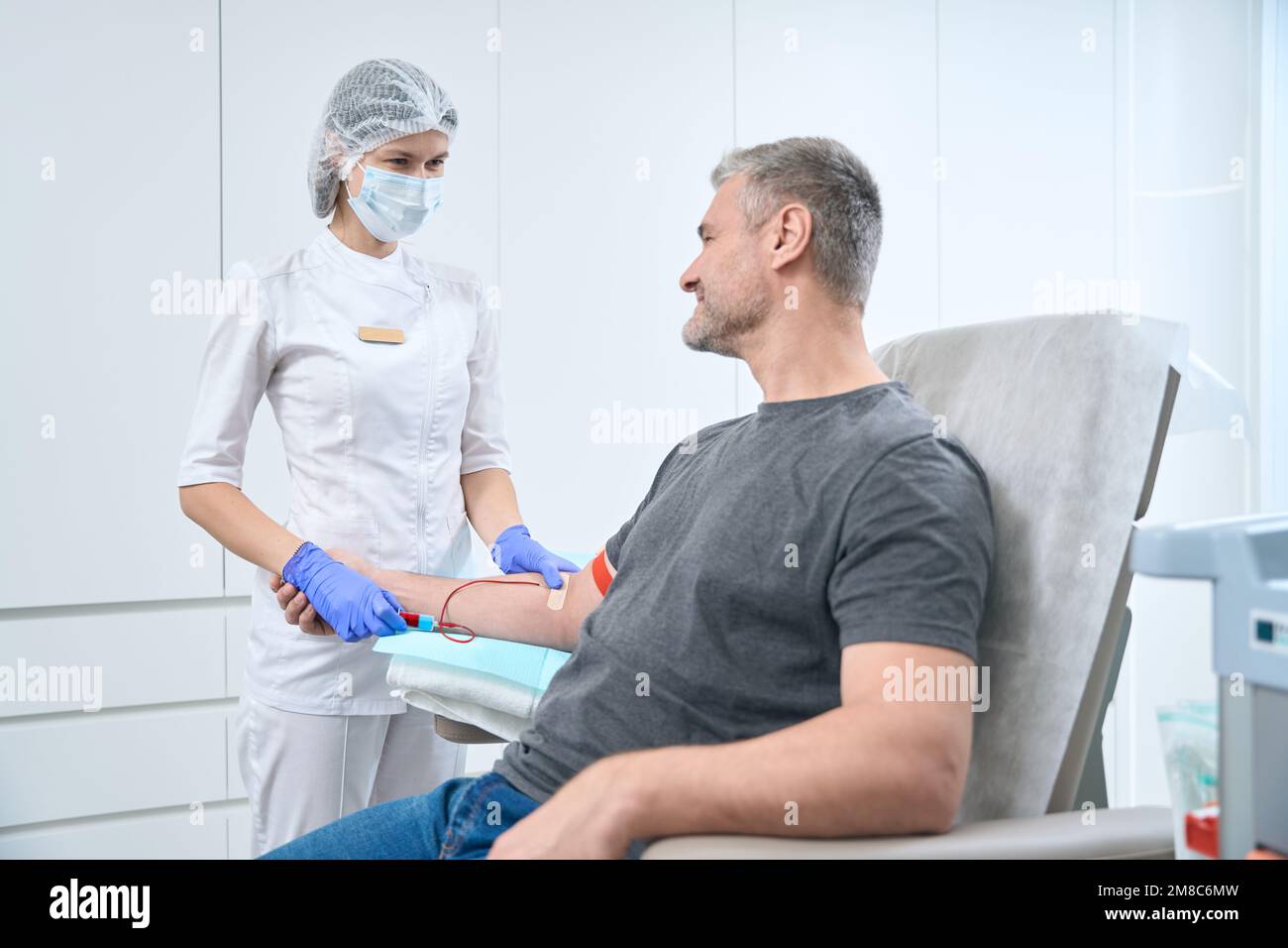 Health worker in medical clothes takes blood sample from man Stock ...