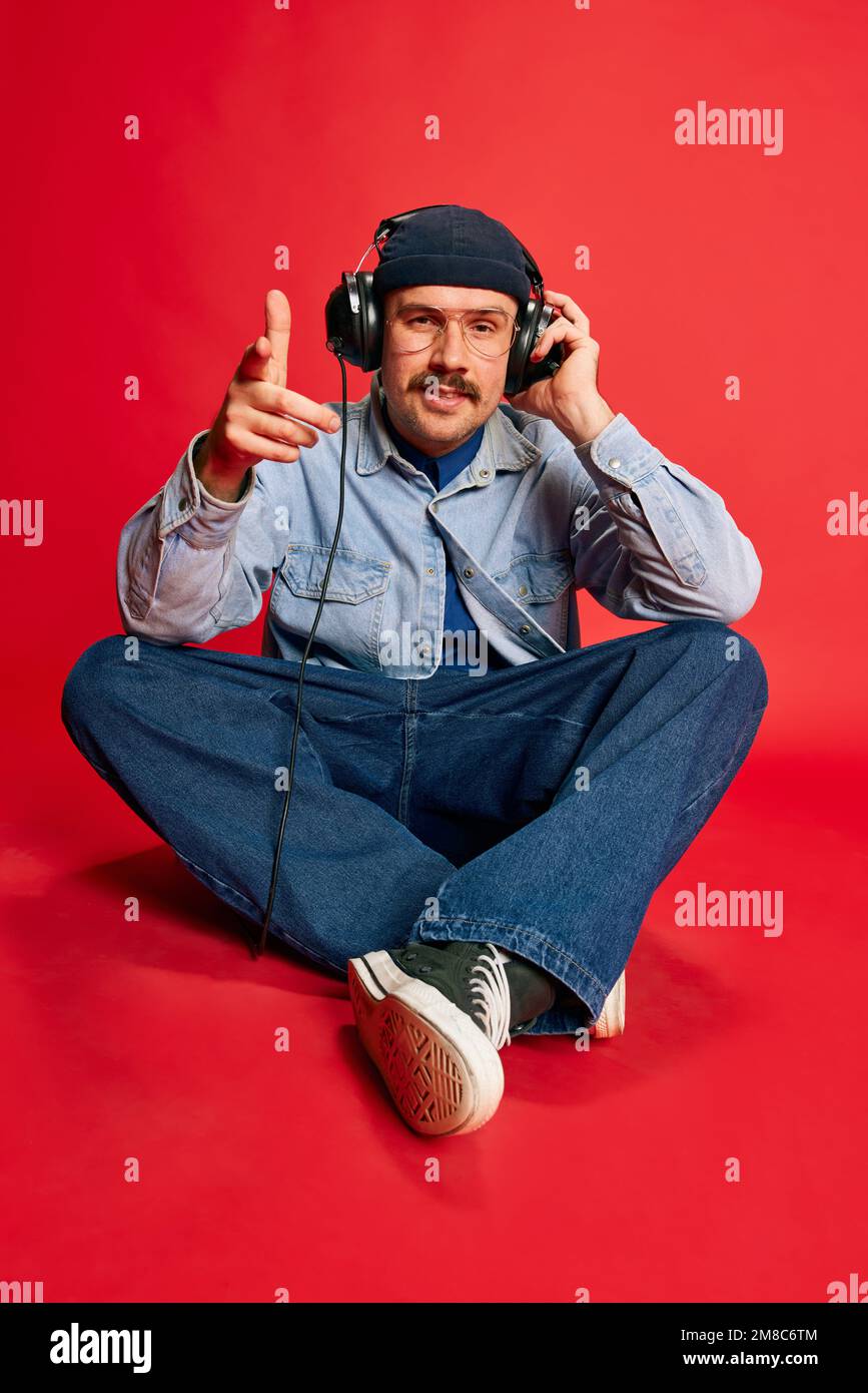 Portrait of man in stylish modern clothes, posing, listening to music ...