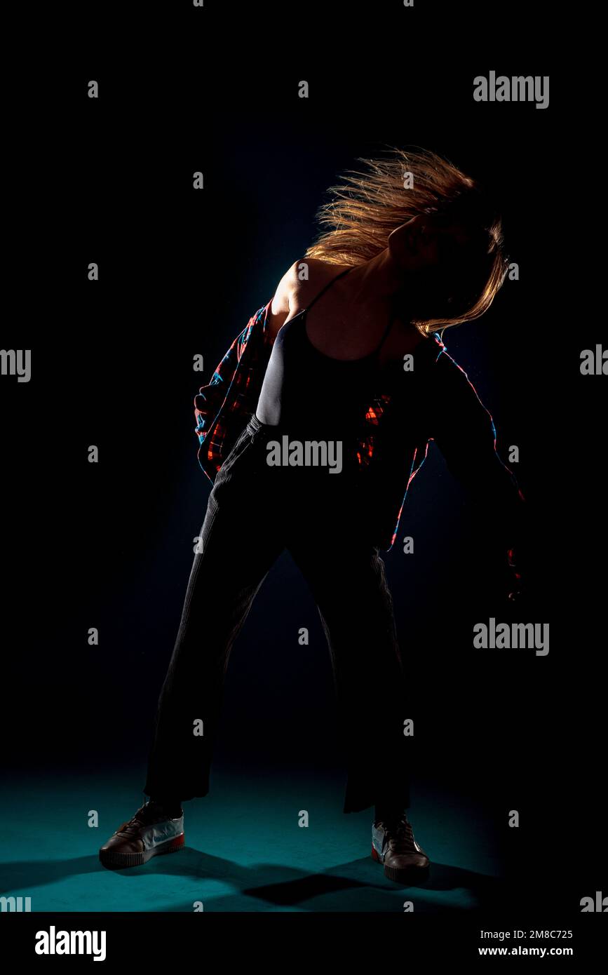 Fit young girl dancer performing a dance routine isolated in the dark ...