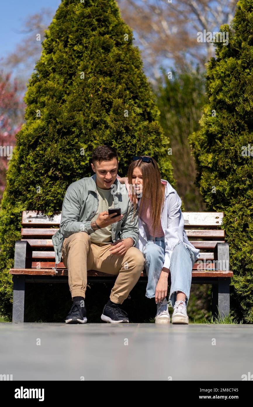 Happy casual couple talking looking each other sitting in a park with a ...