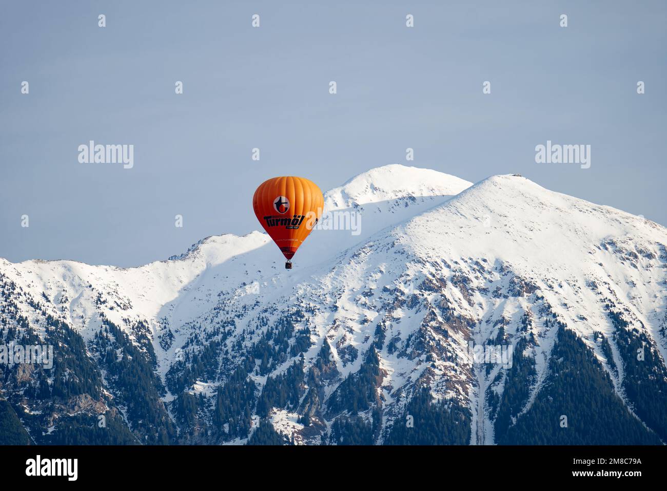 Hot air balloon flying around the mountains covered with snow. A winter ...