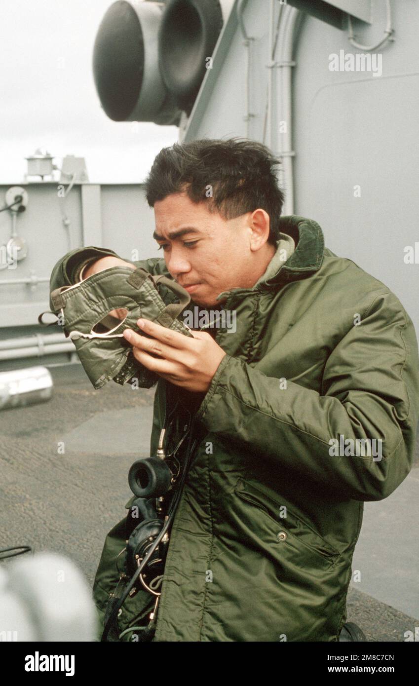 A sailor on the aircraft carrier USS CONSTELLATION (CV 64) dons a cold ...