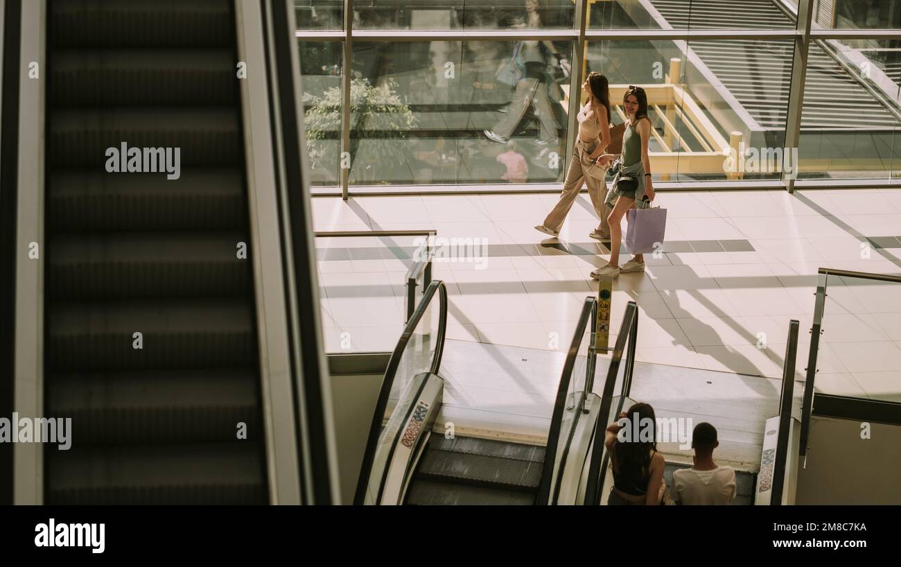 Two amazing girls walking with their shopping bags in the mall near the ...