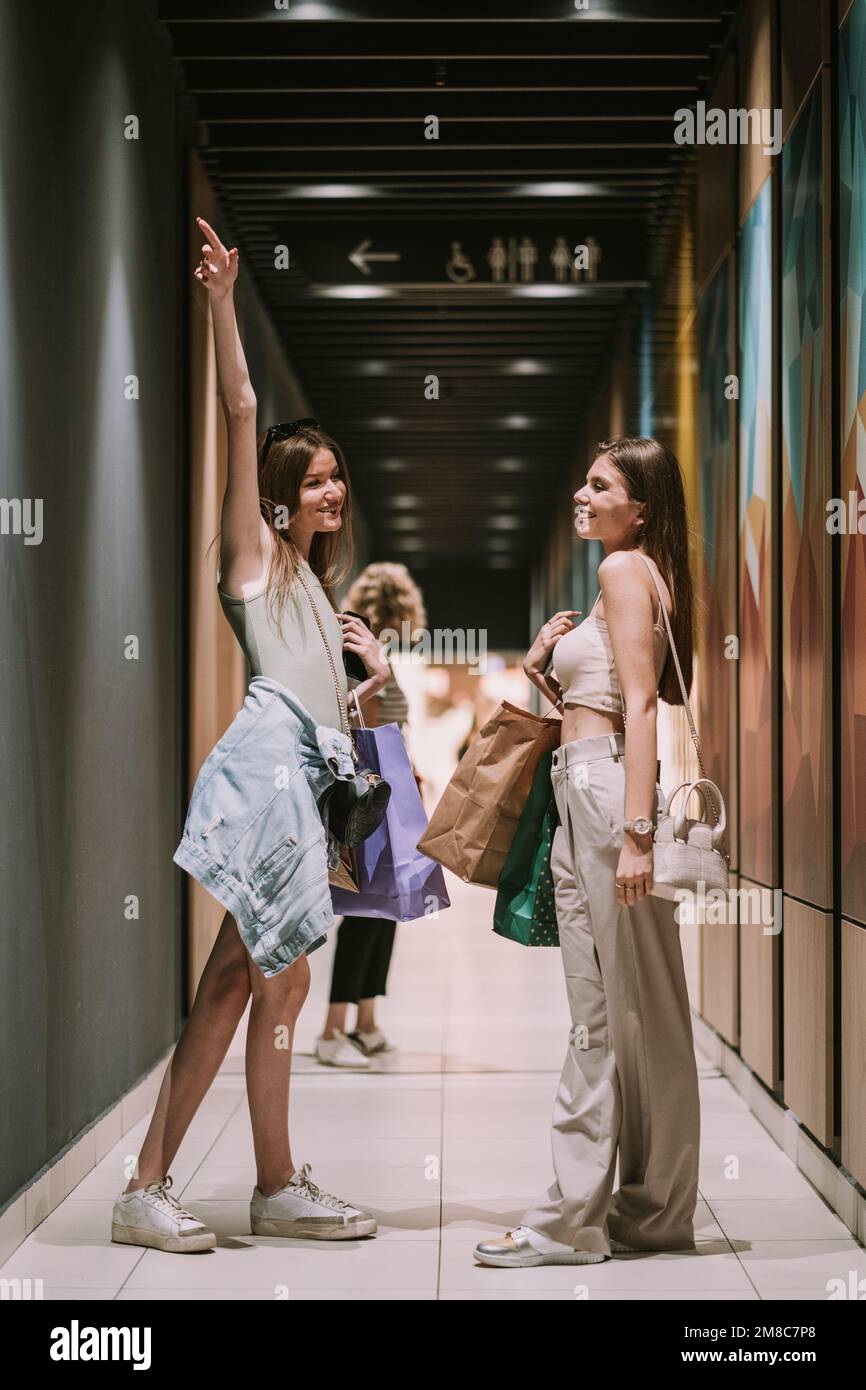 Two beautiful girls standing in the middle of the hallway in the mall ...