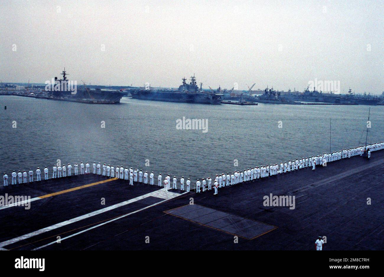 Sailors line the edge of the flight deck as the aircraft carrier USS ...