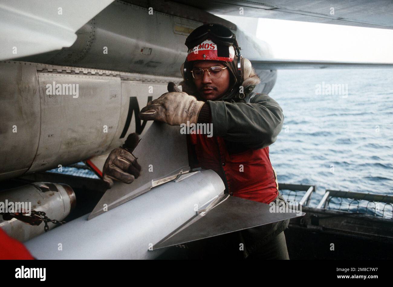 An ordnance crew member inspects an AIM-7 Sea Sparrow missile on an A-7 ...
