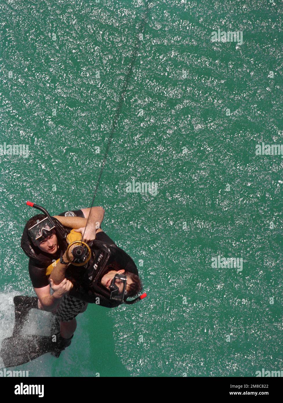 Rescue swimmers are hoisted aboard an SH-3H Sea King helicopter from ...
