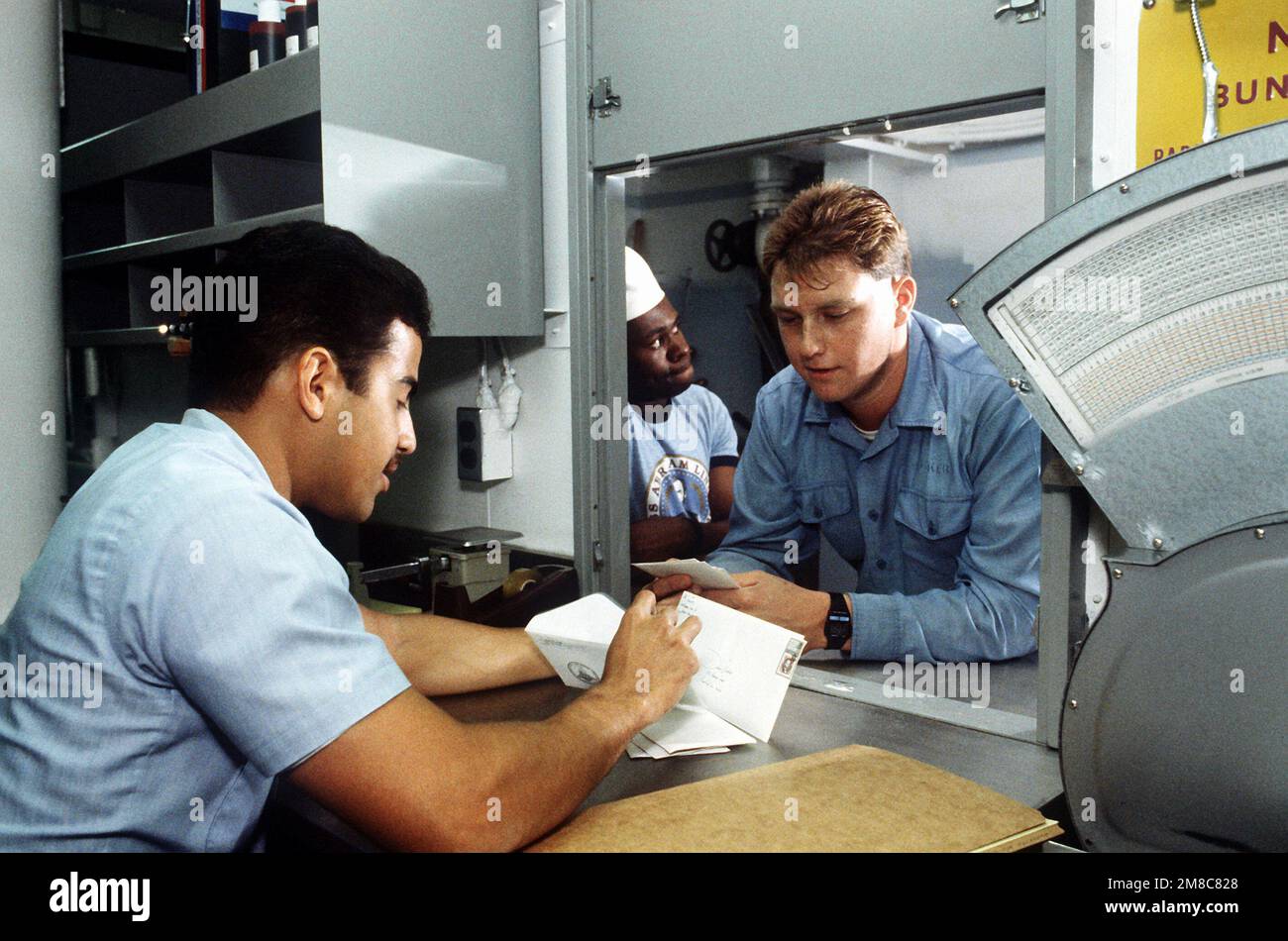 PC Harry Rodriguez checks postage on envelopes as Yeoman Drew Baker ...
