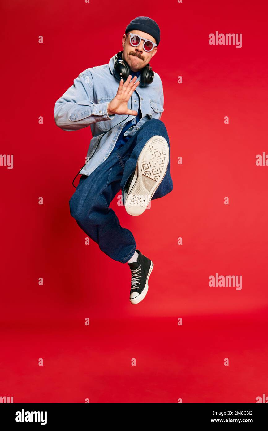 Jump. Portrait of man in stylish modern clothes, oversized jeans, shirt ...