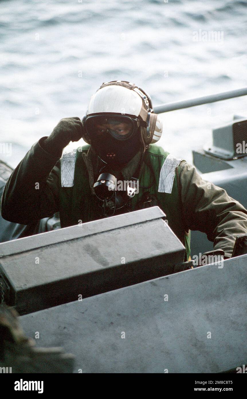Bundled up against the cold, a catapult deckedge operator mans his ...