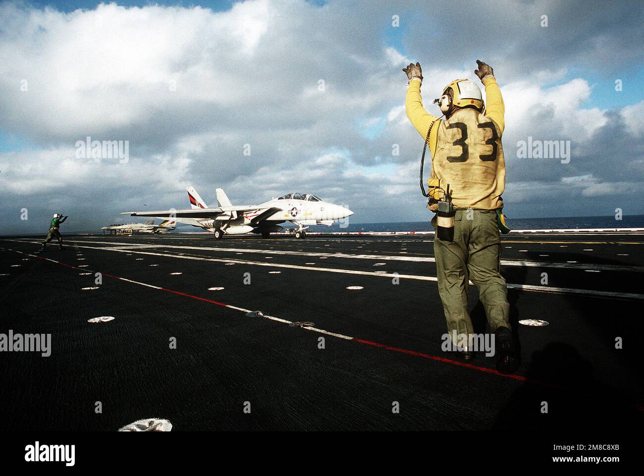 A plane director signals to the pilot of a Fighter Squadron 154 (VF-154 ...