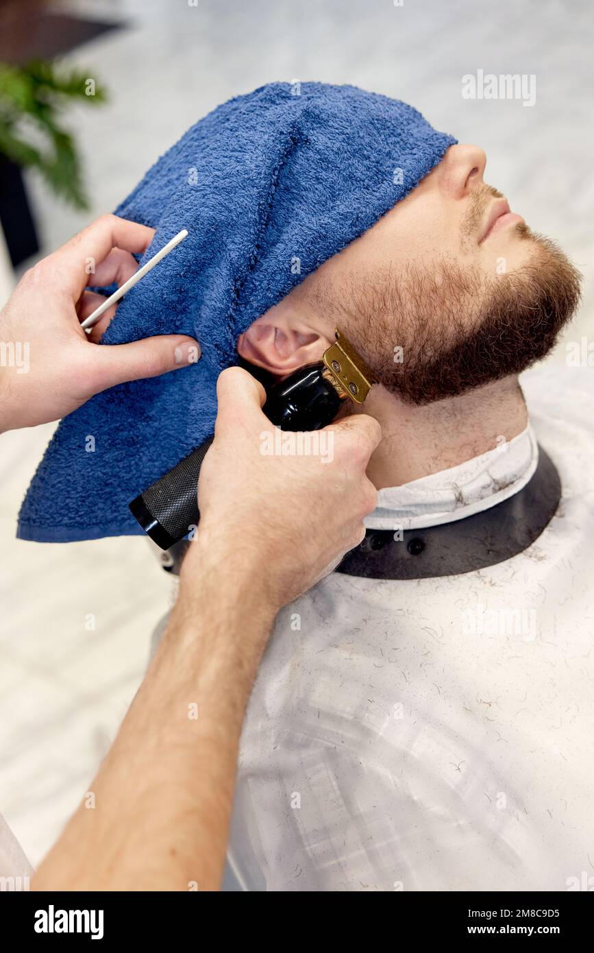 Barber shaving bearded man in barber shop Stock Photo - Alamy