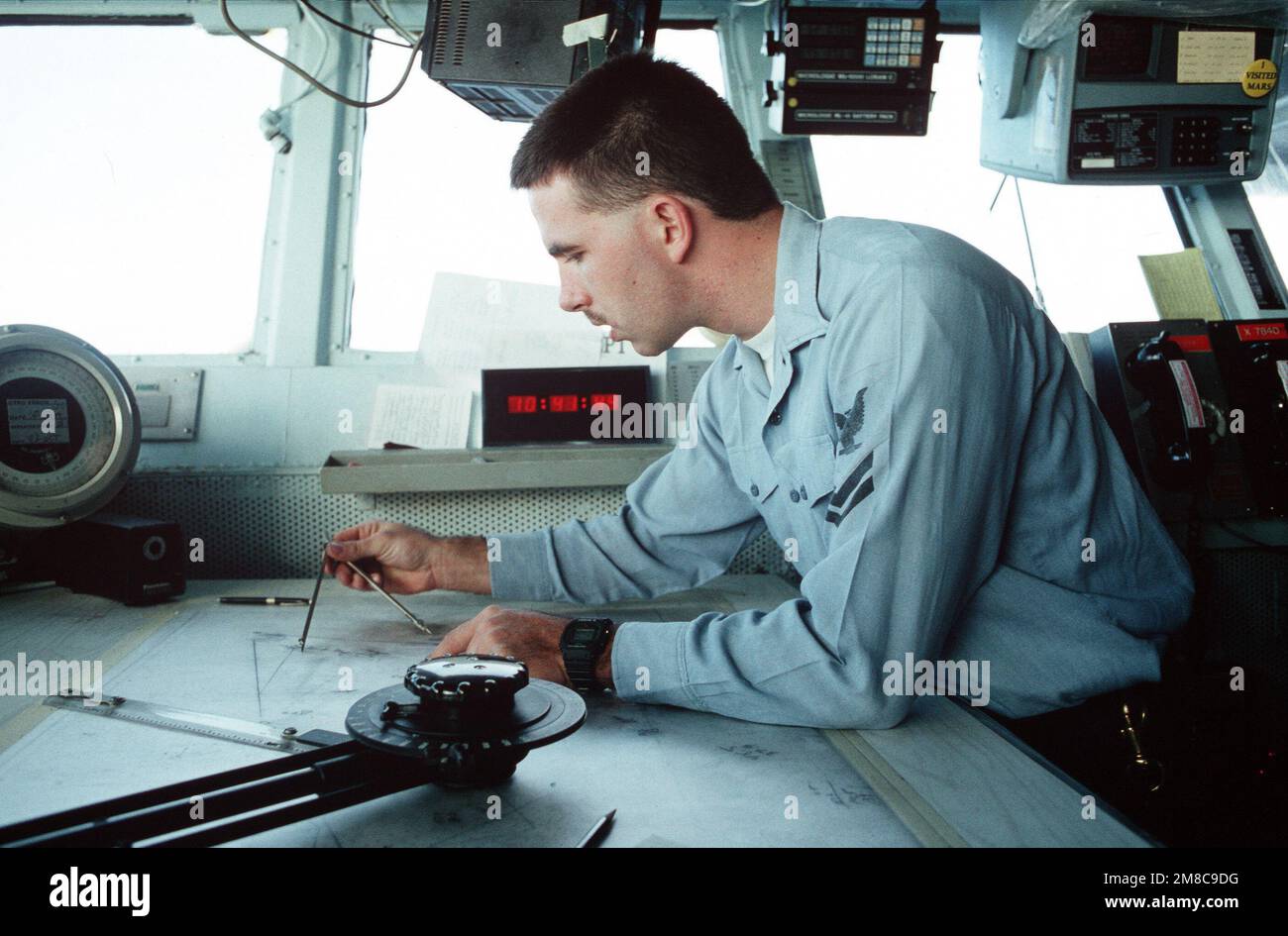 A sailor works at a chart table on the bridge of the aircraft carrier ...