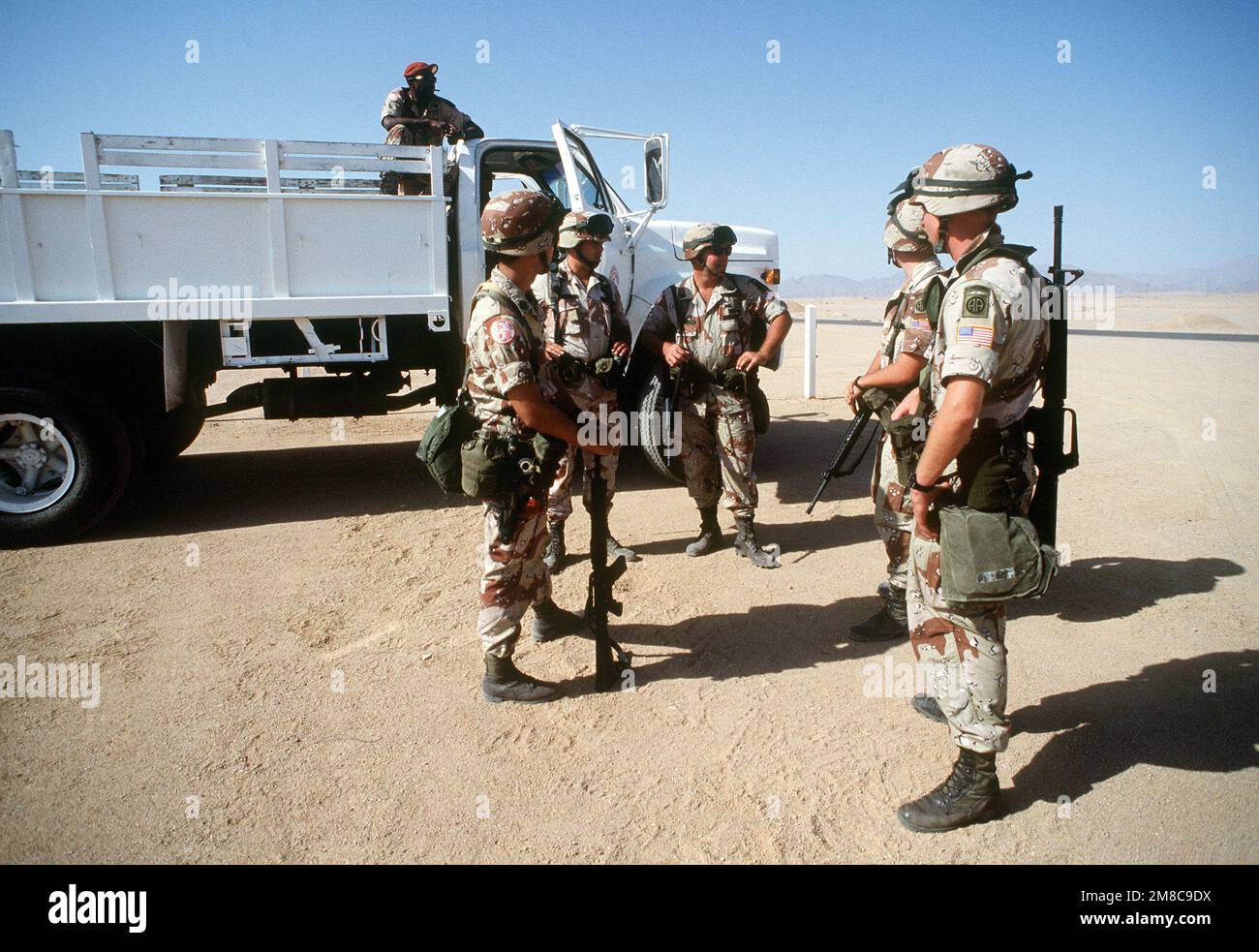 Several soldiers from the 82nd Airborne Division wait to board a truck ...