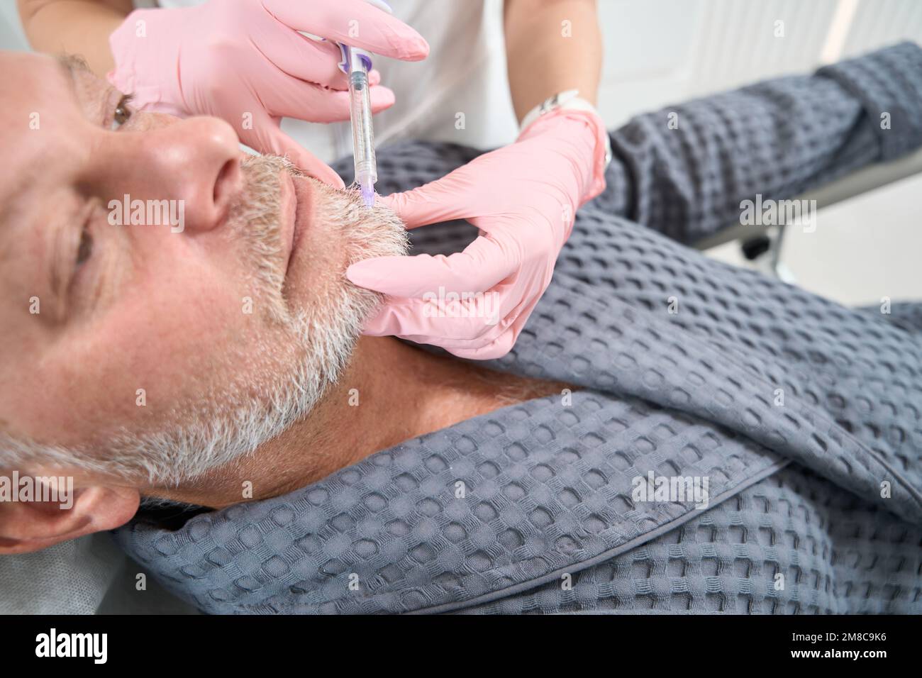 Gray-haired man receives beauty injections in an aesthetic medicine ...