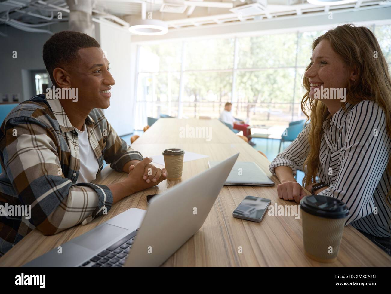 Two happy colleagues talking in office lobby Stock Photo - Alamy