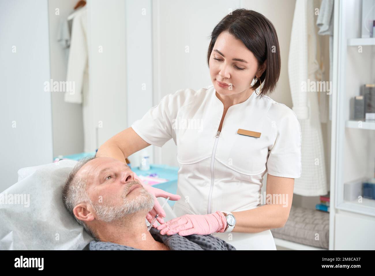 Patient lies calmly in medical chair, doctor gives him injections Stock ...