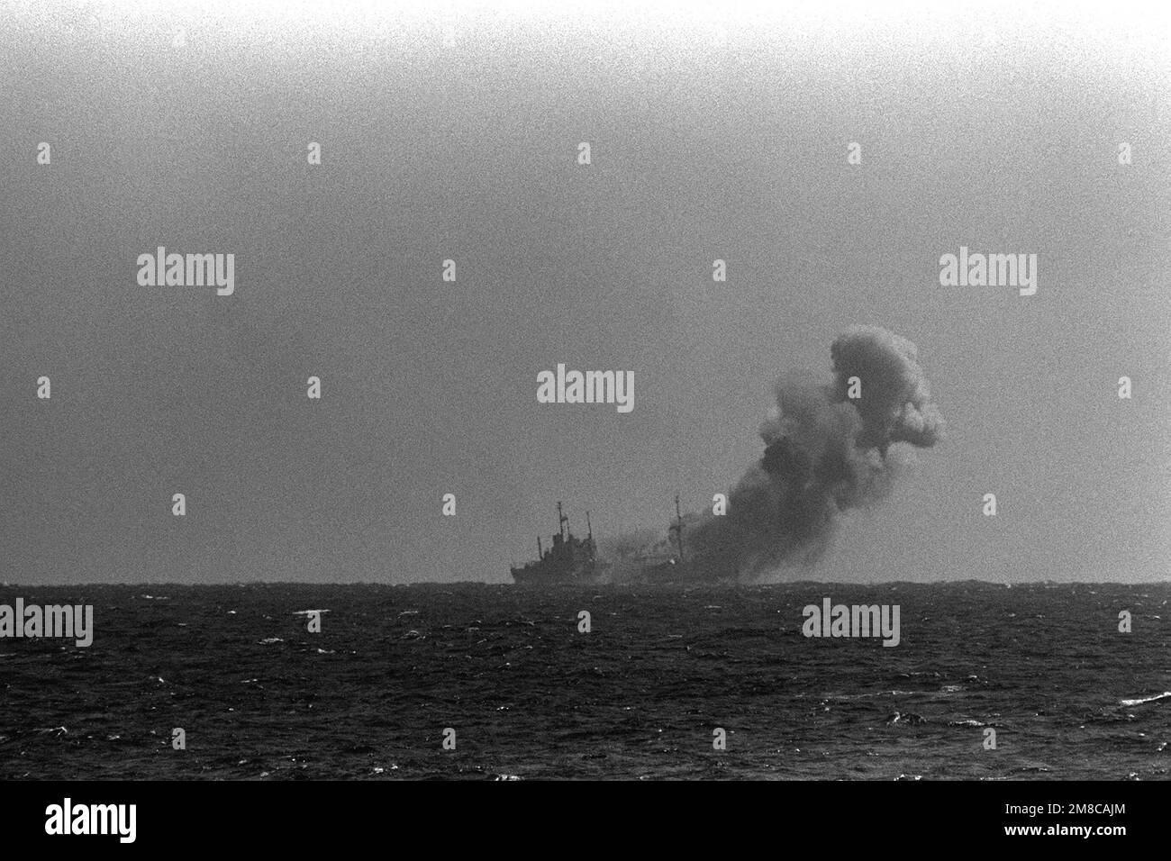 Smoke rises from the target ship being fired on by the battleships USS ...