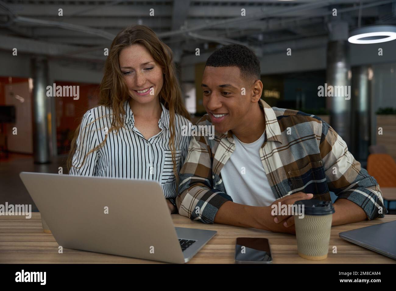 Smiling employees looking at laptop screen in the lobby Stock Photo - Alamy