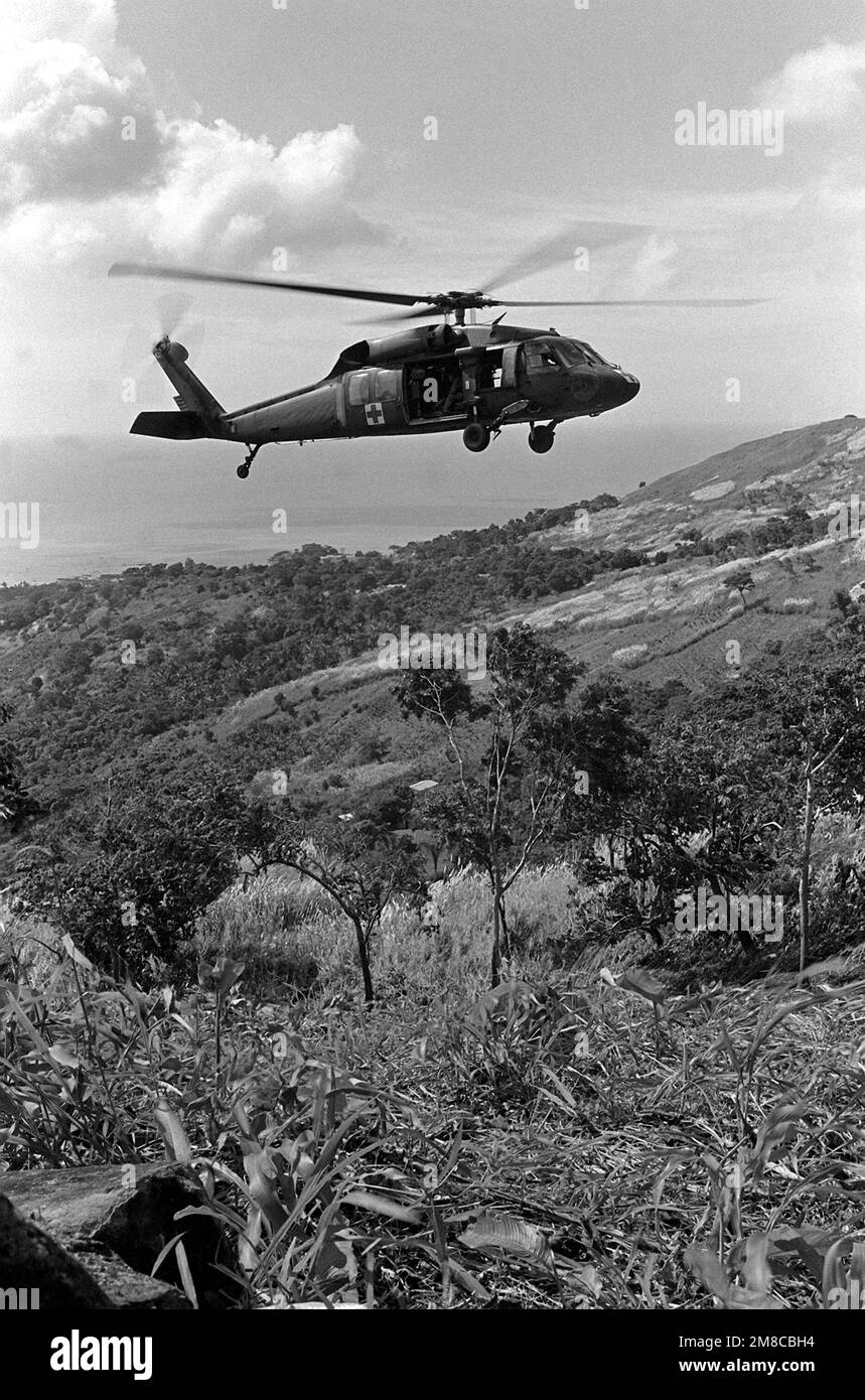 A UH-60 Black Hawk helicopter hovers over a hillside in order to pick ...