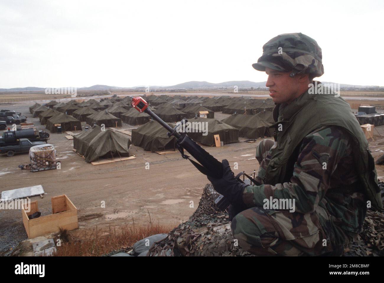 An airman armed with an M-16 rifle guards his post at a tent city ...