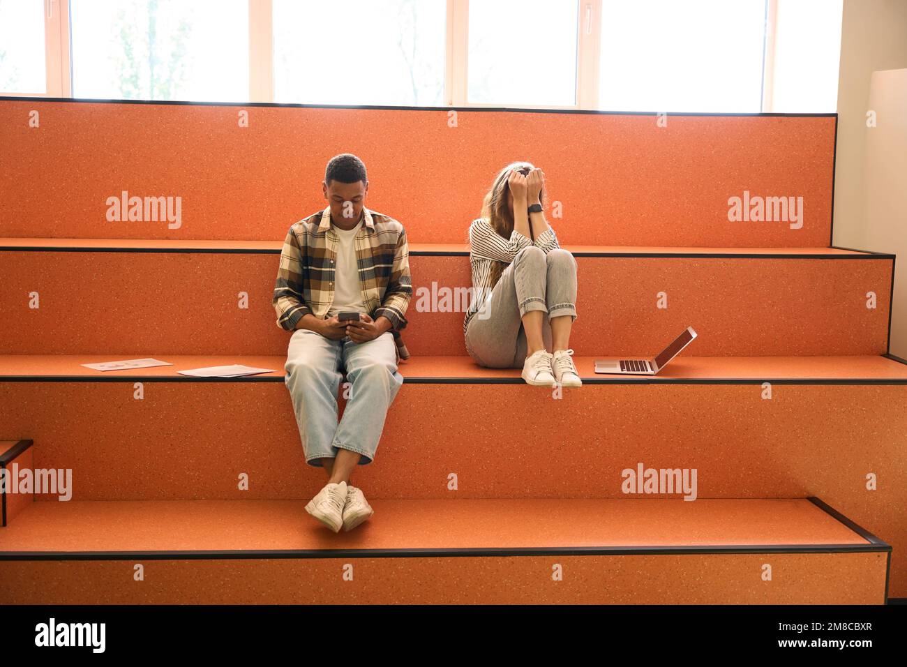 Young man using phone while lady sitting eyes closed next to him Stock ...