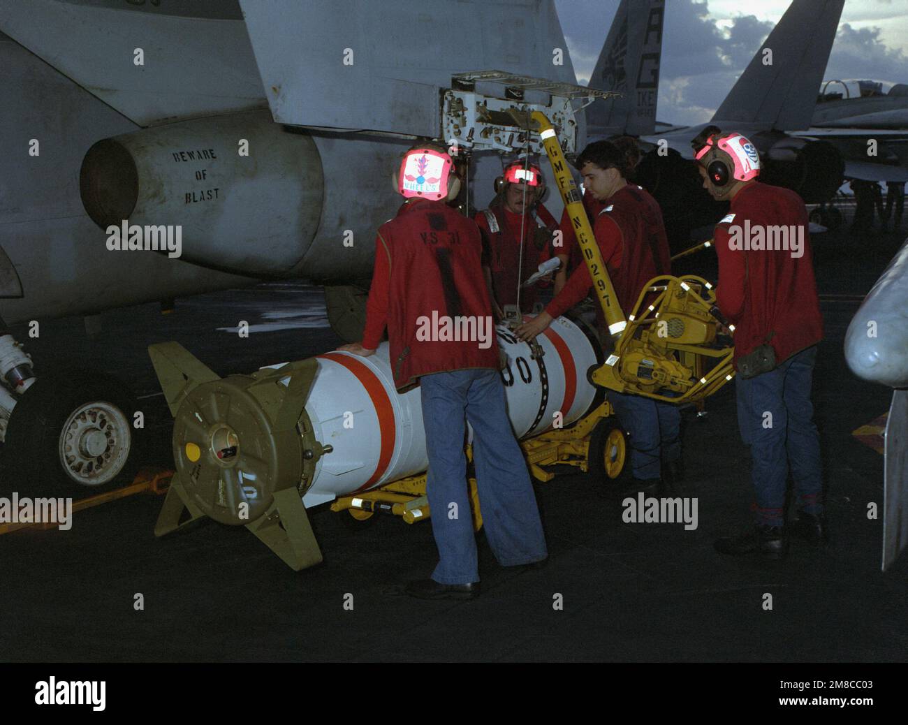 Ordnancemen use an HLU-196 bomb hoist to raise a Mark 56 mine onto the ...