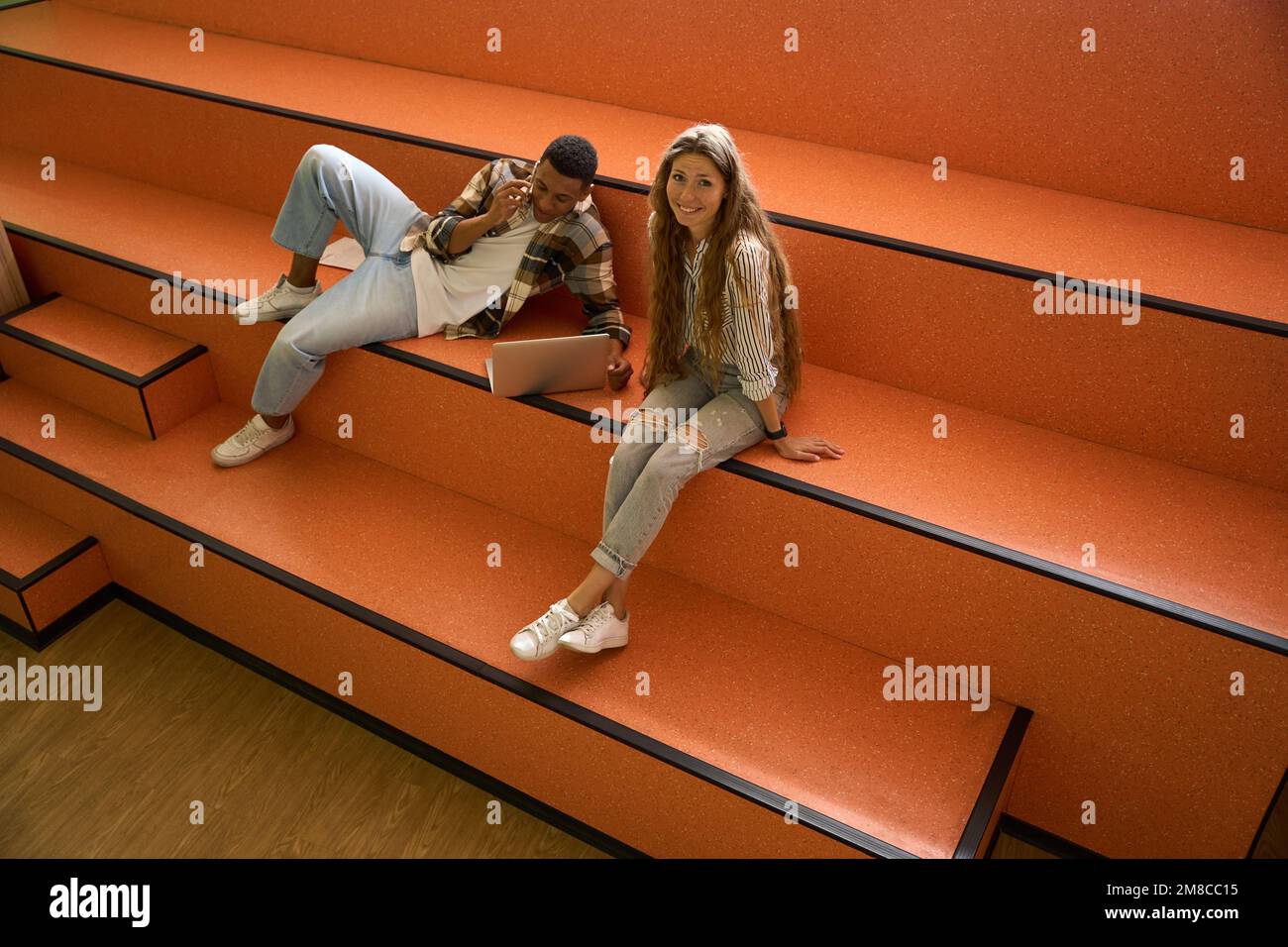 Happy students are sitting on steps together Stock Photo - Alamy