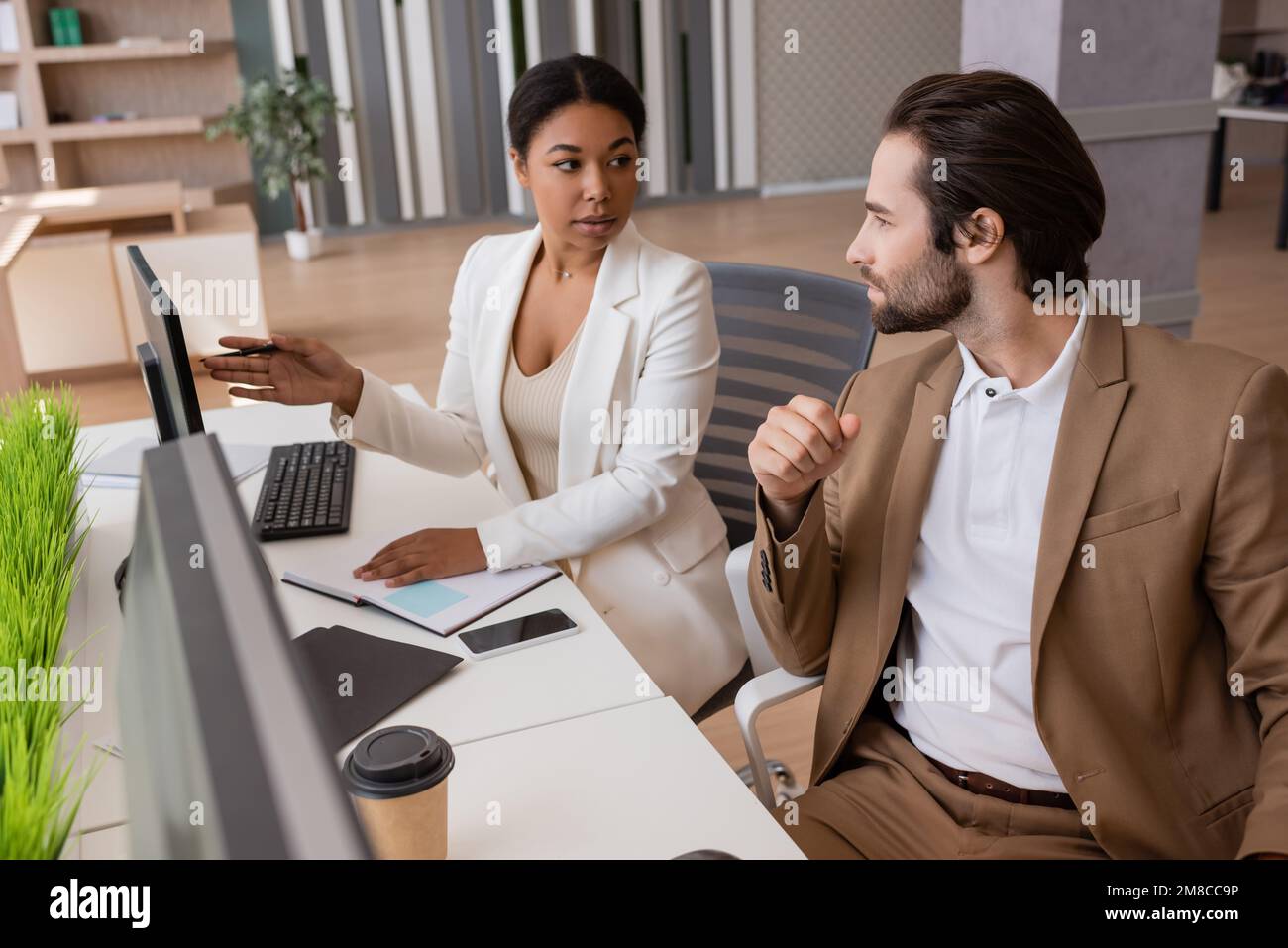 multiracial businesswoman pointing at computer monitor and talking to ...