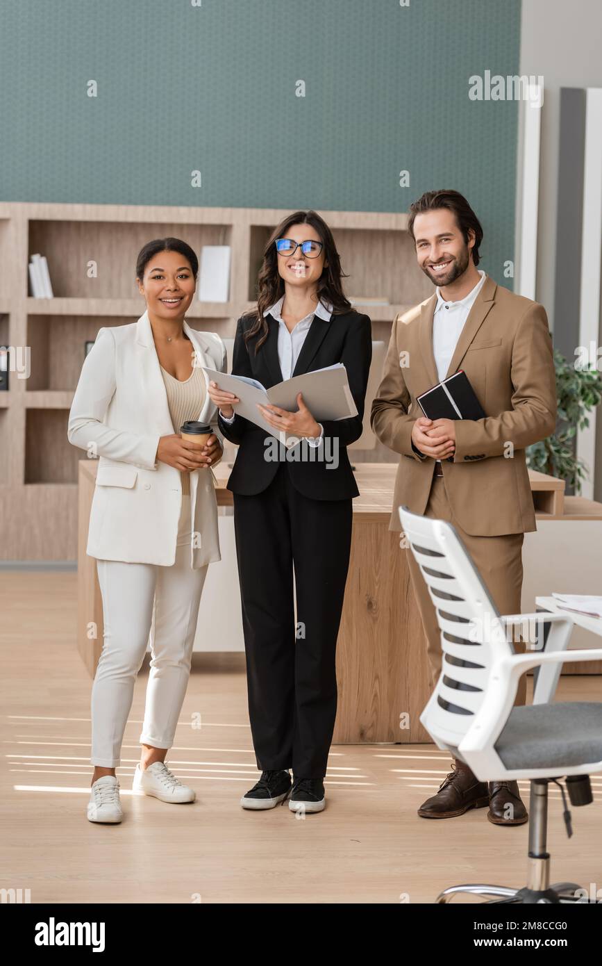 full length of happy multiethnic business people in formal wear looking ...