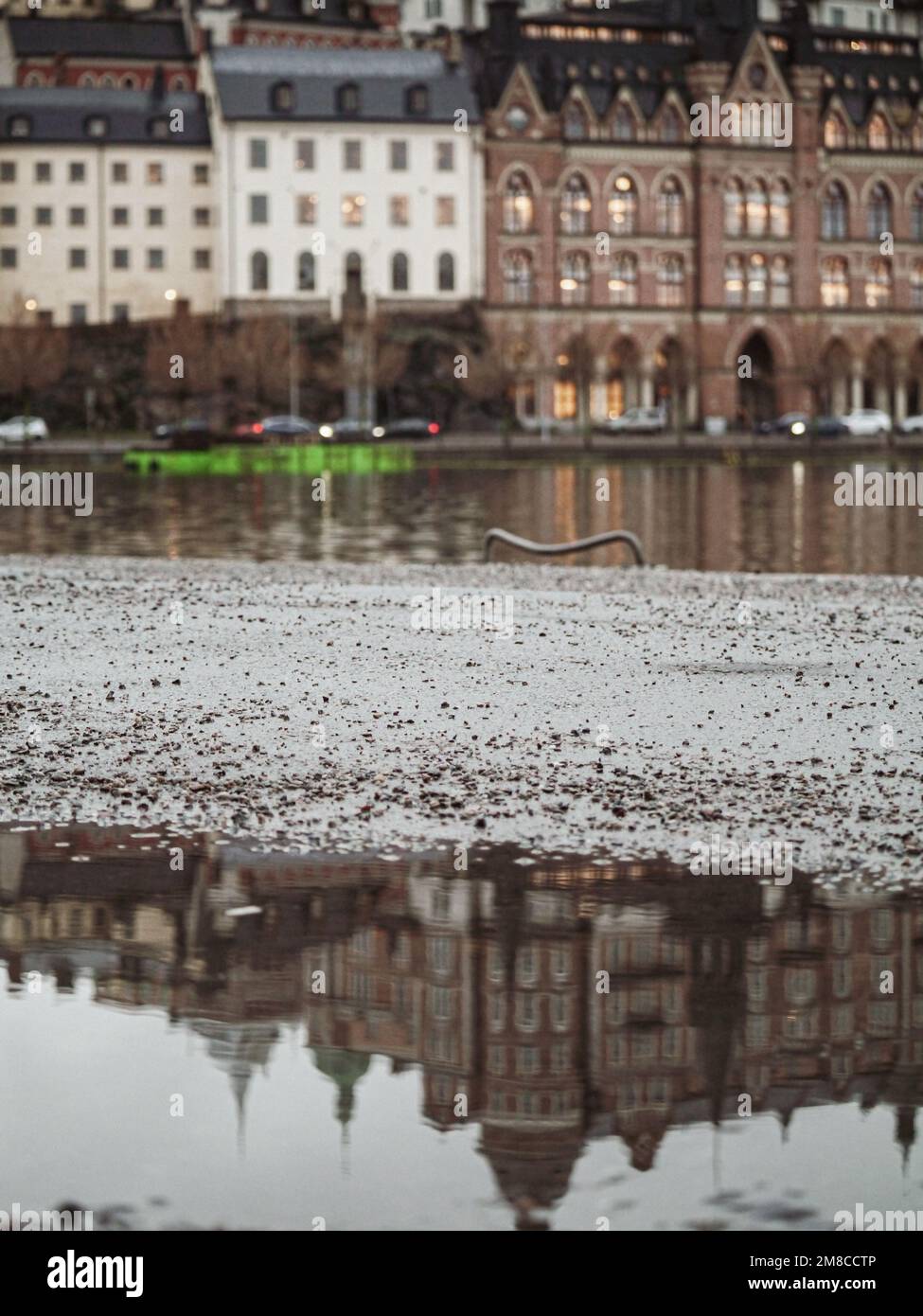 Reflection of buildings in a puddle next to river Stock Photo - Alamy