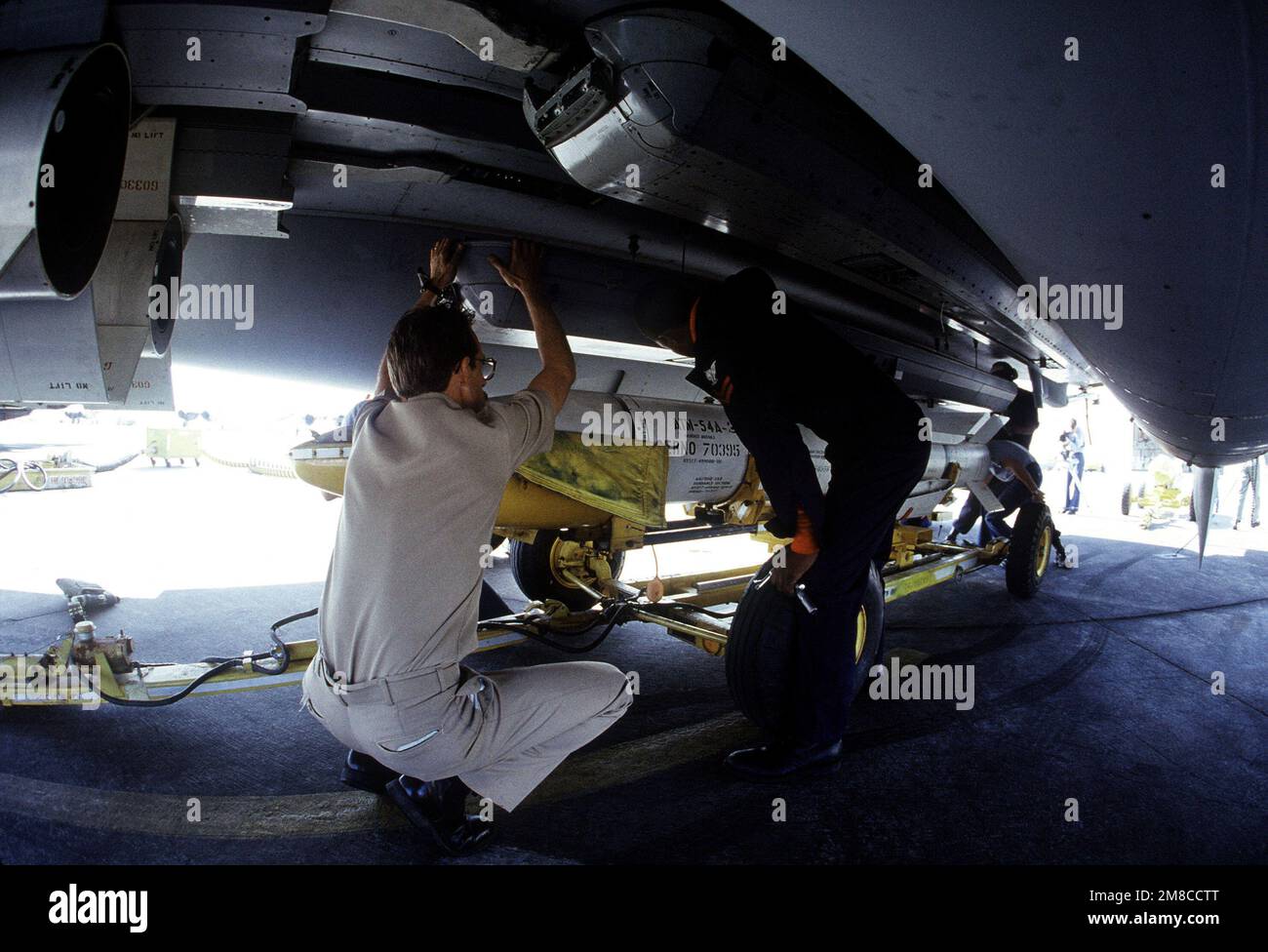 An officer supervises the loading of an ATM-54A dummy Phoenix missile ...