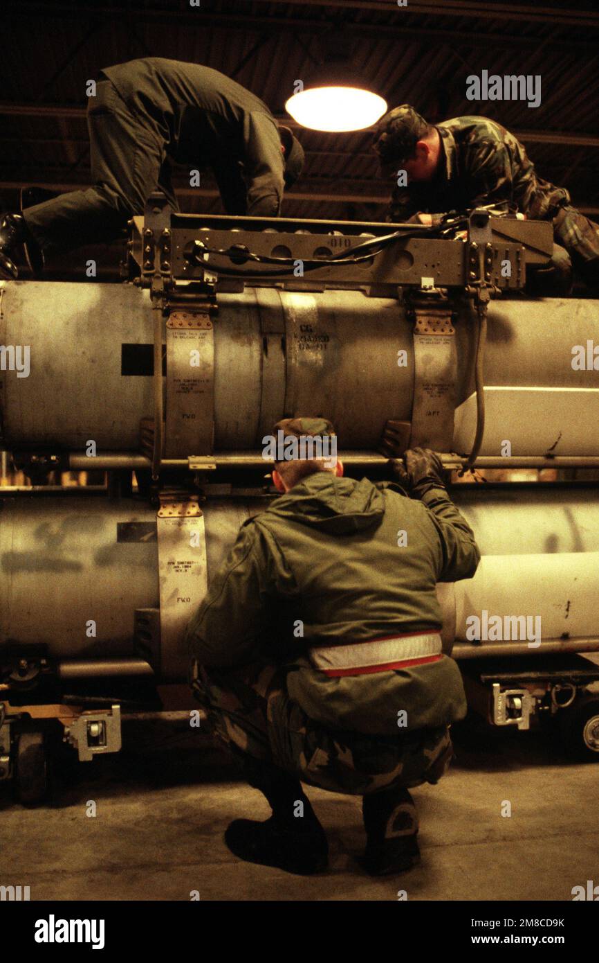 Three airmen from the 42nd Munitions Maintenance Squadron secure a pair ...