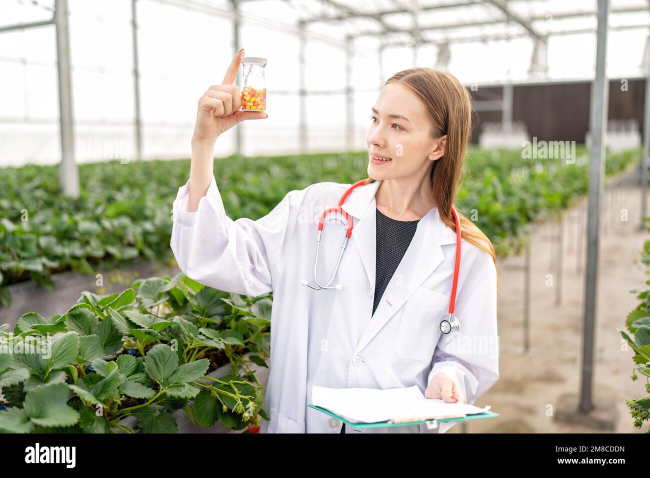 Doctor nutritionist in greenhouse farming proudly showing bottle of ...