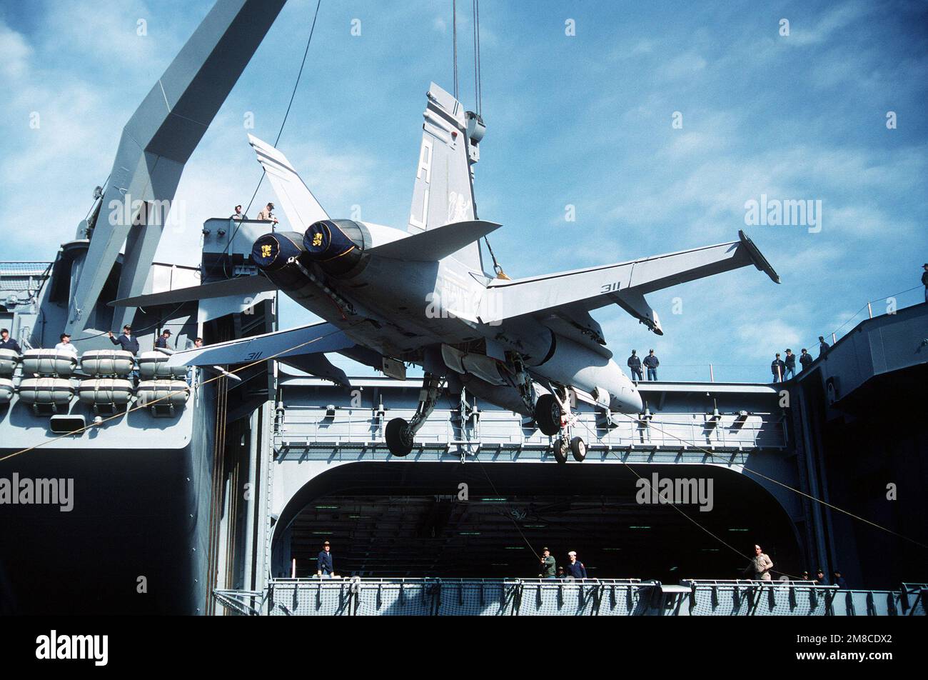 A shipboard crane lifts an F/A-18 Hornet aircraft on the nuclear ...