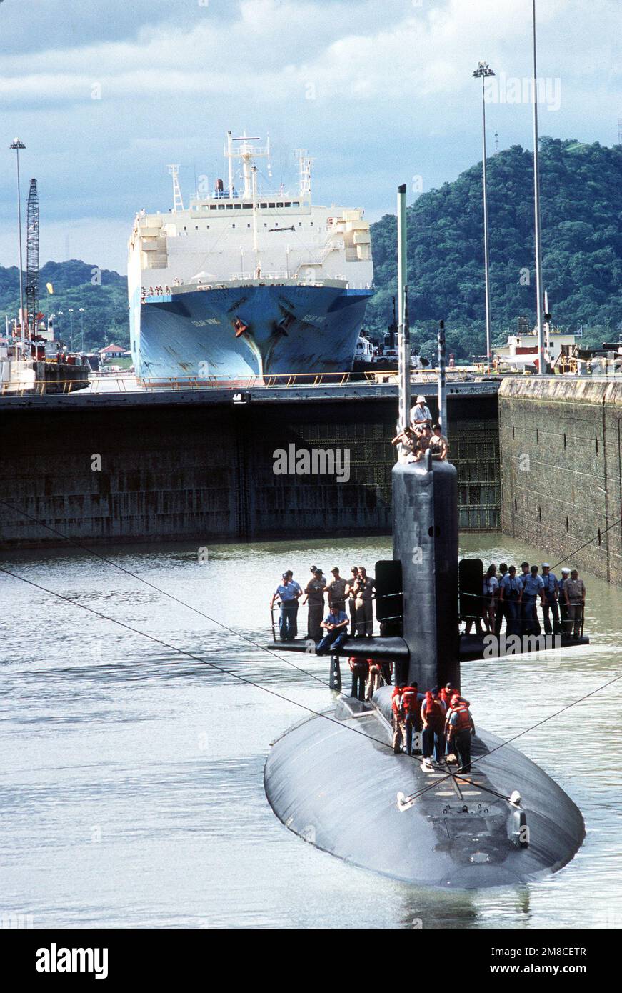 Crew members stand on the sail and diving planes of the nuclear-powered ...