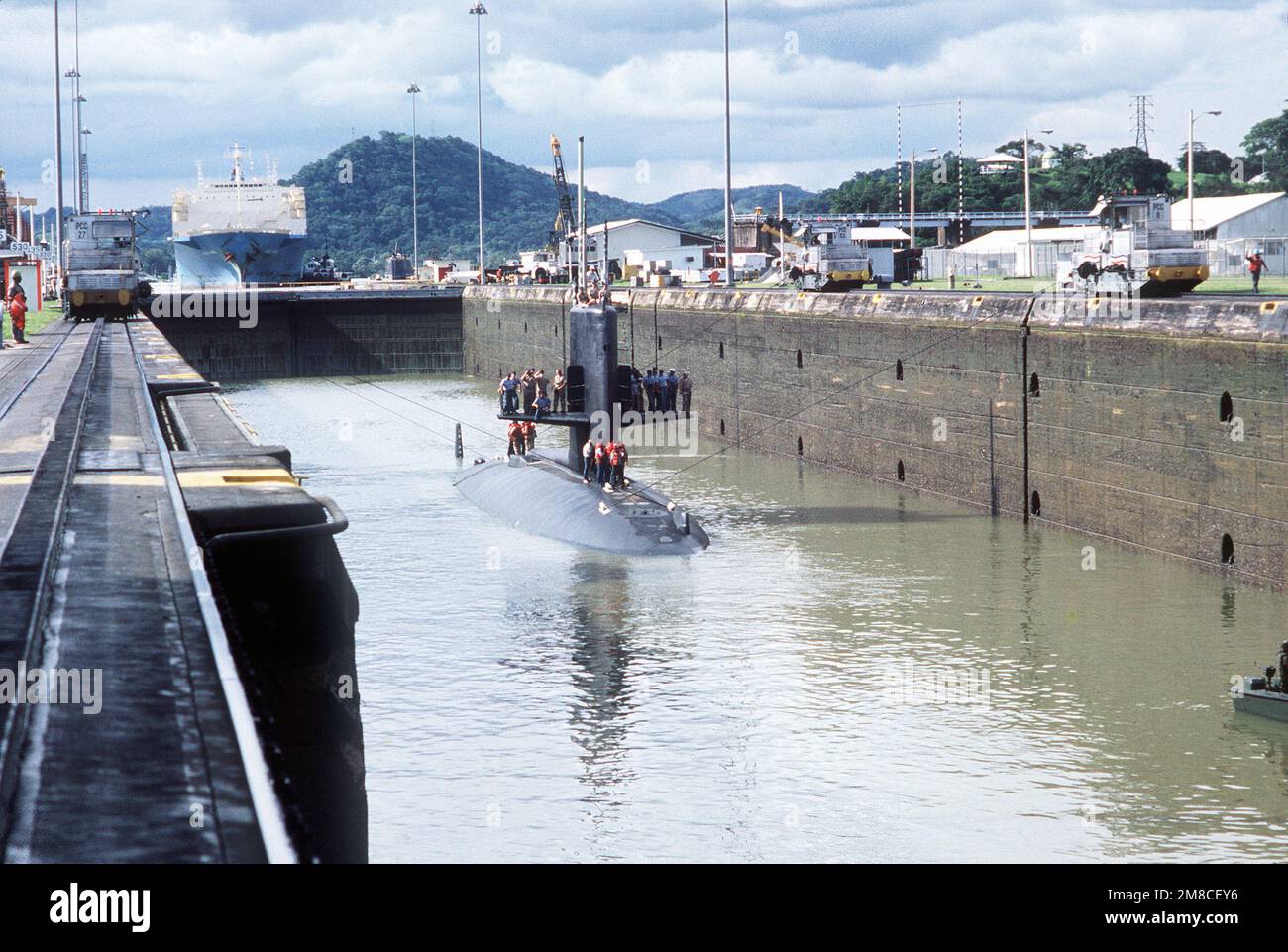 Crew members stand on the sail and diving planes of the nuclear-powered ...