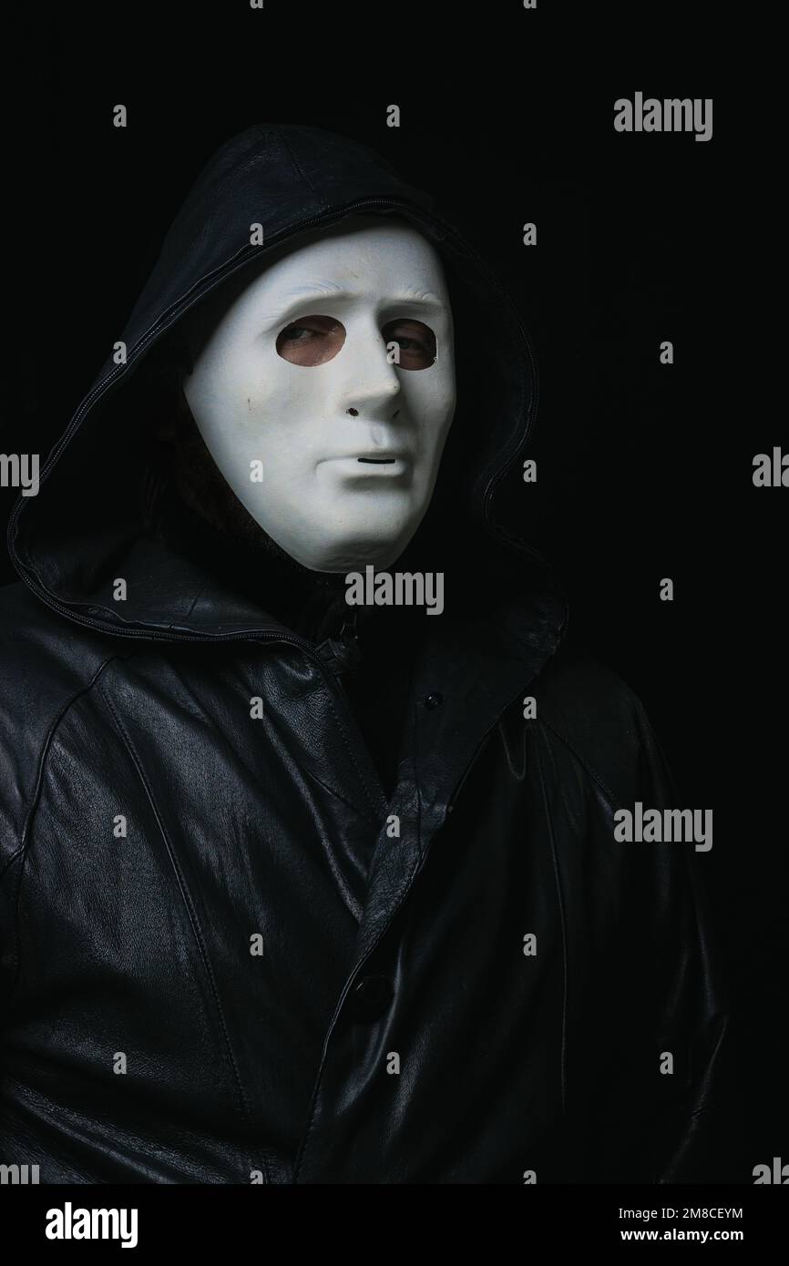 Man in terrible face mask staring at camera against dark background ...