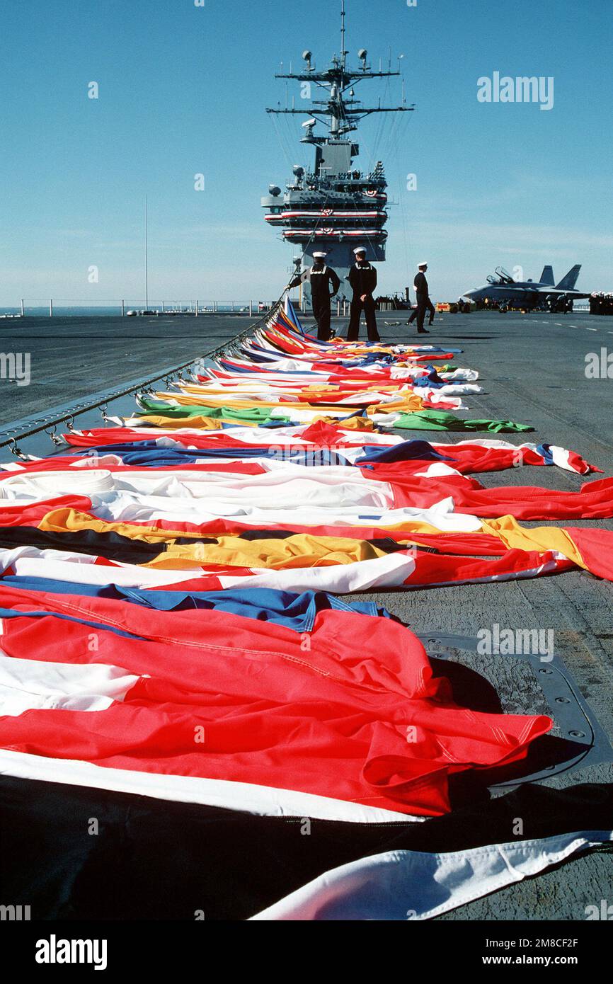 Sailors stand ready to hoist the flags of the nuclear-powered aircraft ...