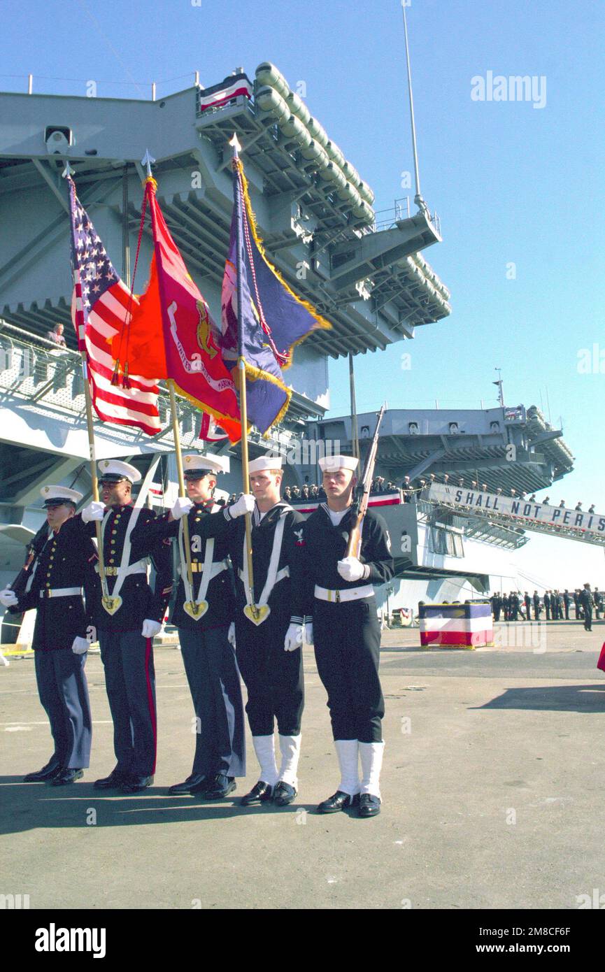 A joint Navy/Marine Corps color guard stands on the pier beside the ...