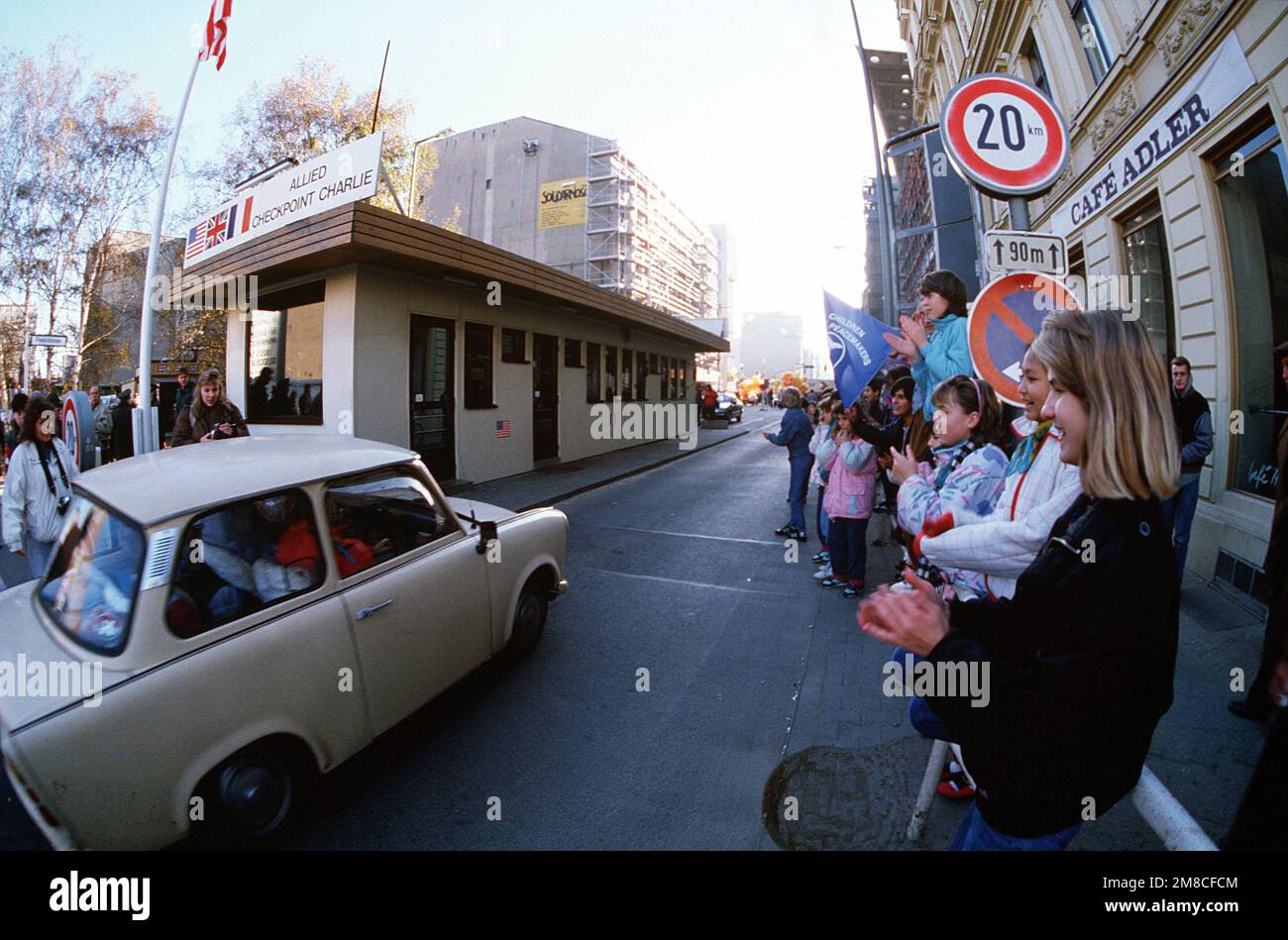 West German children applaud as East German visitors drive through ...