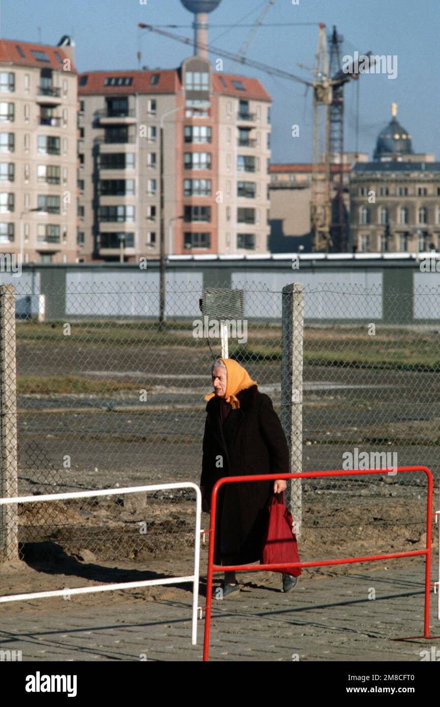 An old woman walks through the newly created opening in the Berlin Wall ...