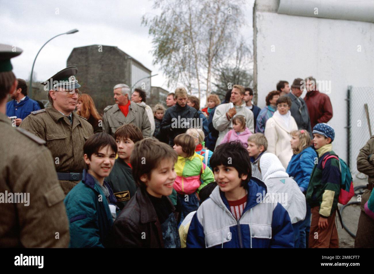 An East German policeman watches as visitors wander through the newly ...