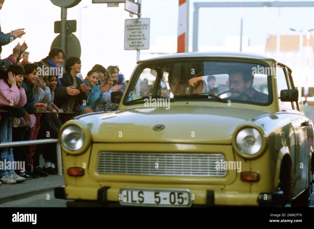 West German children applaud as an East German couple drive through ...