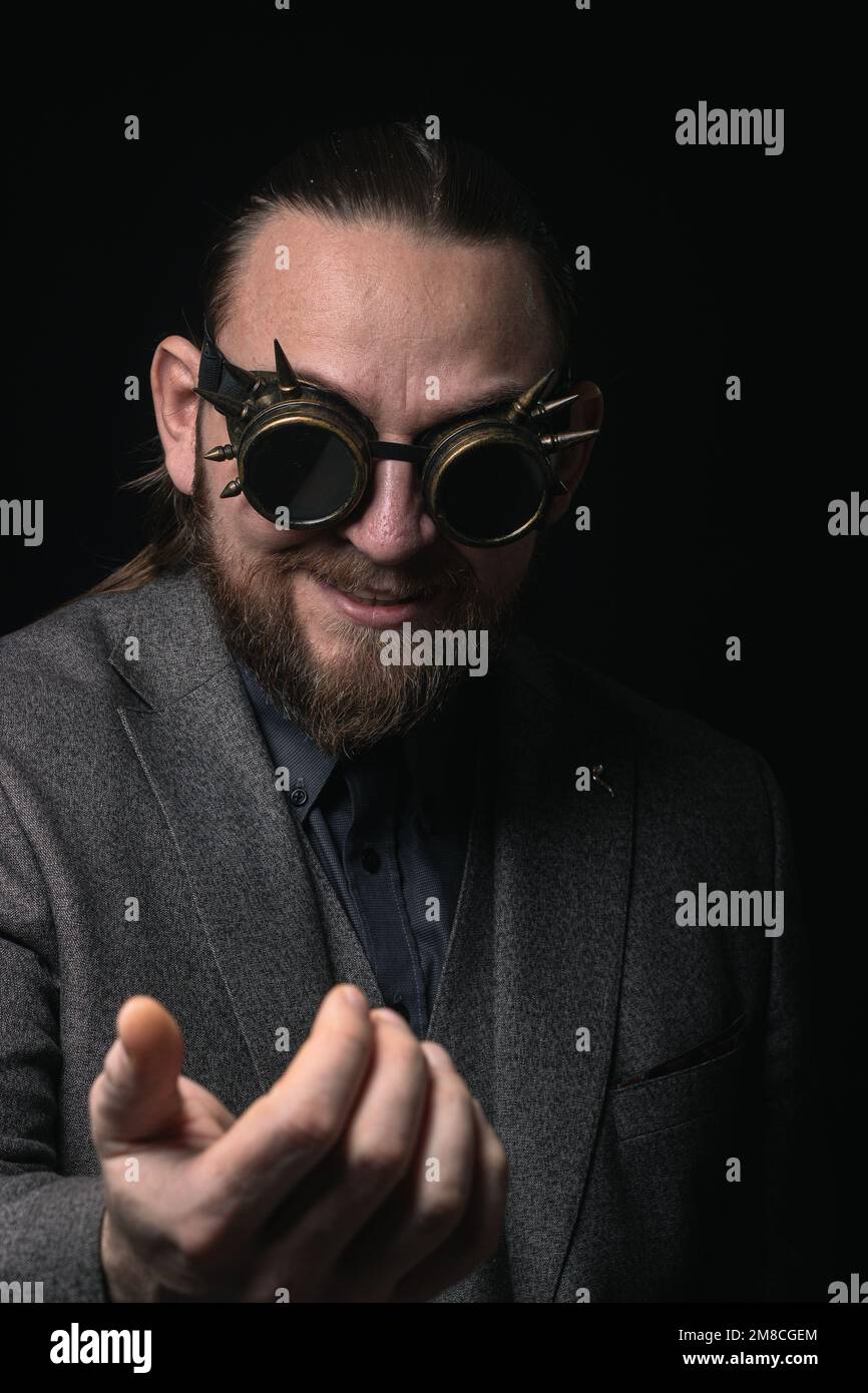 charismatic man in a classic suit and steampunk goggles on a black ...