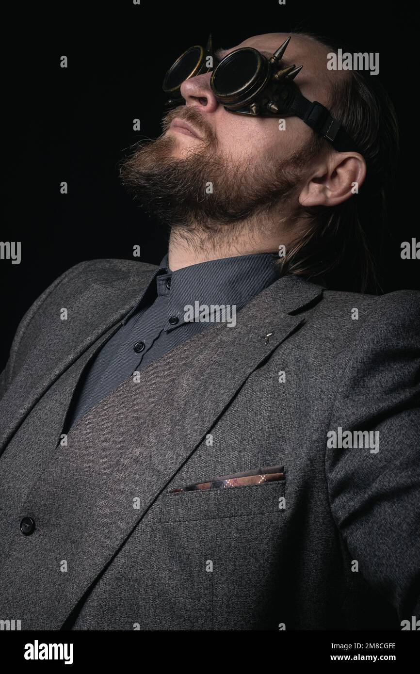 charismatic man in a classic suit and steampunk goggles on a black ...